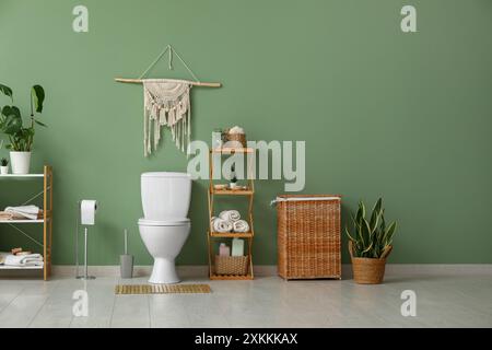Toilet bowl, shelving units and laundry basket near beige wall in ...