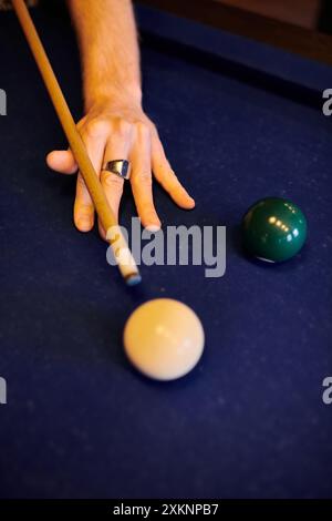 Hand holding billiard cue aiming at cue ball on pool table with other ...