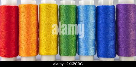 Rainbow colour sewing threads on white background Stock Photo - Alamy