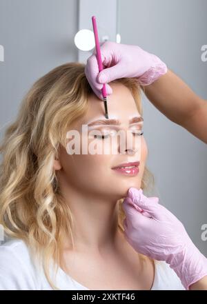 Professional beautician doing eyebrow tattoo at woman face. Permanent ...
