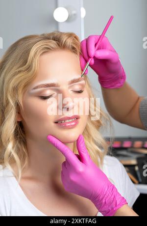 Professional beautician doing eyebrow tattoo at woman face. Permanent ...