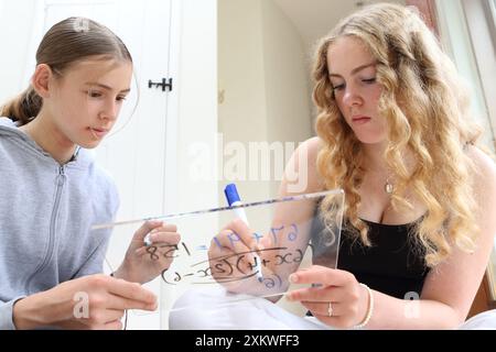 Girls doing maths math sitting on floor writing on whiteboard with pens algebra fractions ...