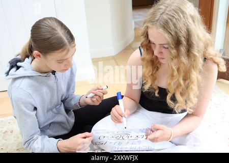 Girls doing maths math sitting on floor writing on whiteboard with pens ...