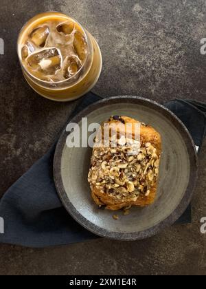 Iced coffee and freshly baked pastry on rustic ceramic. Dark background ...