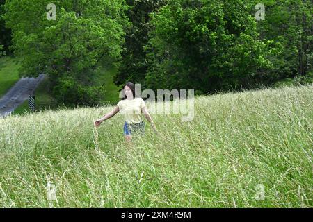 Female teen walks slowly through a field of green grass. Her thoughts ...