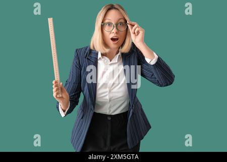 Mature female math teacher with ruler and calculator on grey background ...