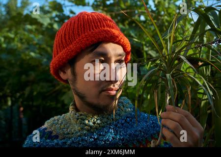 a man in a poncho looks at a plant Stock Photo - Alamy