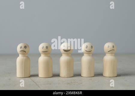 Wooden figures showing different emotions on grey table Stock Photo - Alamy