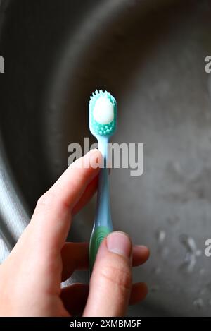 a blue toothbrush in the hand with white toothpaste Stock Photo - Alamy
