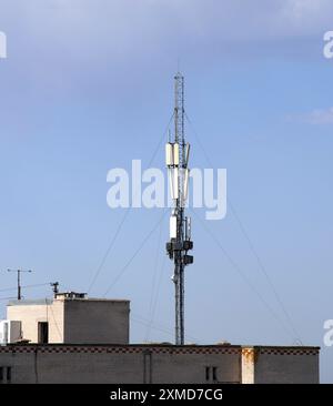 5G cellular tower installed on rooftop building against blue sky ...