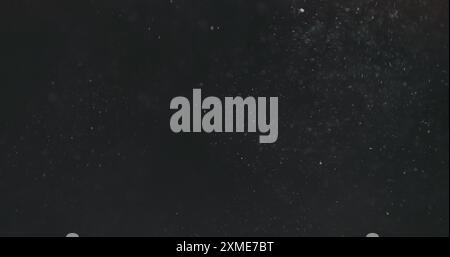 Macro shot of fast moving dust particles on a black background, wide ...