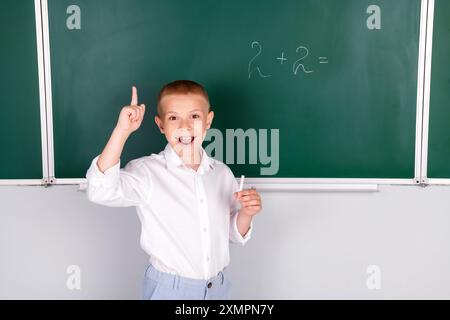 Photo of clever adorable boy standing in class room solve math task ...