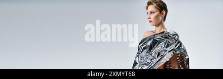 A woman draped in metallic fabric poses against a blue background Stock ...