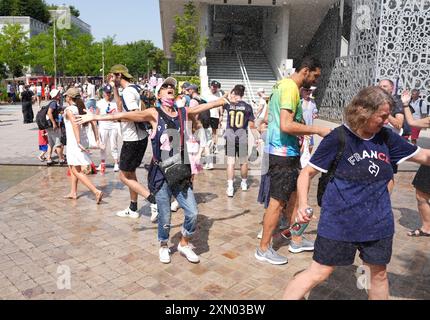 Spectators cool off in a mist of water at Roland-Garros on the fourth ...