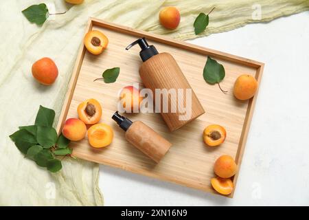 Bottles of cosmetic products with fresh apricots on white tile ...