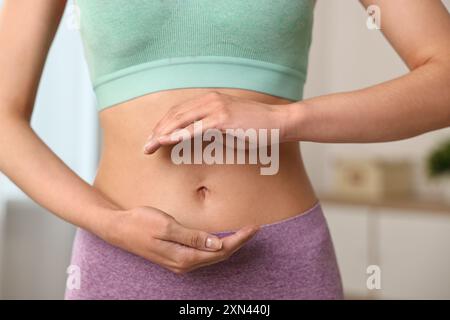 Healthy digestion. Woman holding something near her belly on light blue ...