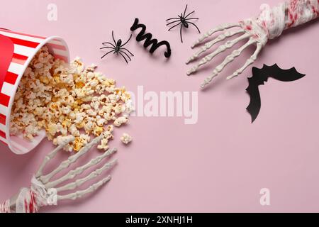 Bucket with tasty popcorn, skeleton hands and clapperboard for ...