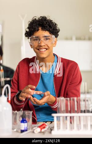 Wearing safety goggles, teenager conducting science experiment in high ...