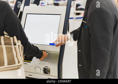 Woman passenger doing self check in scanning boarding pass at airport ...