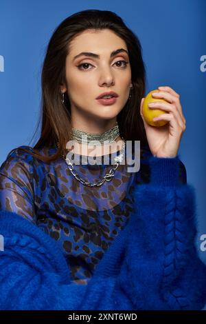 A young woman in a blue fuzzy jacket and black leather pants poses ...