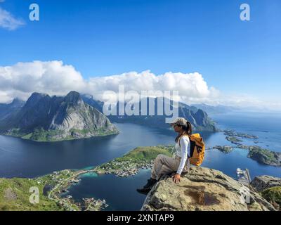 A lone hiker perches on a rocky ledge, gazing across the stunning ...