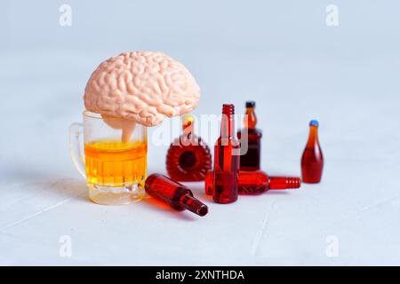 Anatomical model of a human brain surrounded by liquor bottles. Alcohol ...