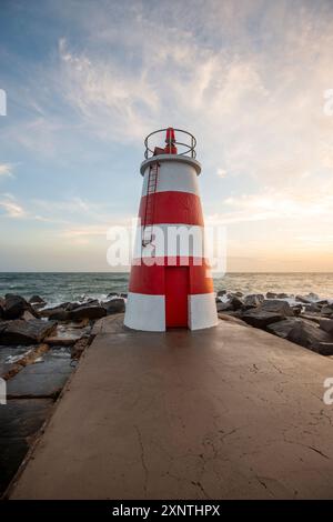 Red and white painted stripy lighthouse with blue sky and cloud in the ...