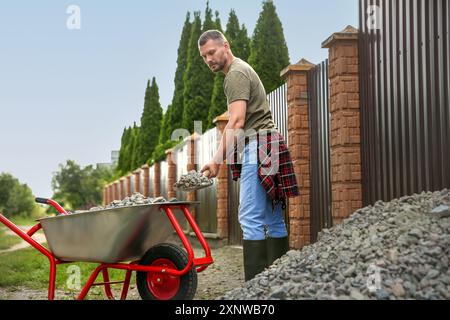 Man with shovel loading stones into wheelbarrow outdoors, closeup Stock ...