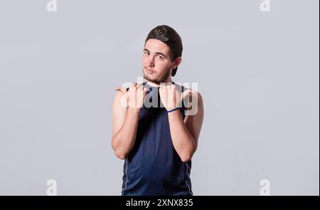 friendly young man pointing to his side and looking into the camera ...