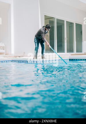 Man cleaning swimming pool with suction hose. Person cleaning a ...