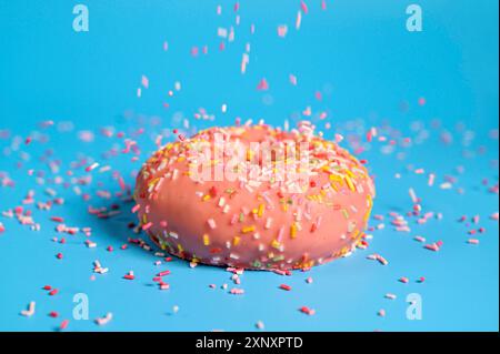 Sprinkles falling from top on Tasty pink strawberry donut. Delicious ...