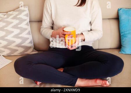 Crop anonymous female sitting in lotus pose with hands in Gyan mudra ...