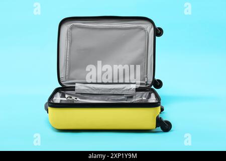 Open empty suitcase on light grey background, top view. Space for text ...