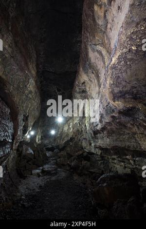 Dimly lit cave interior with rocky surfaces and shadows, creating a ...