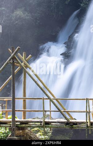 The landscape of a bamboo footbridge across a waterfall near a Karen ...