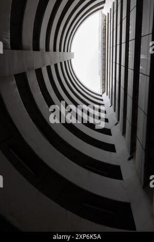 Bottom view of circular car parking garage against white clouds and ...