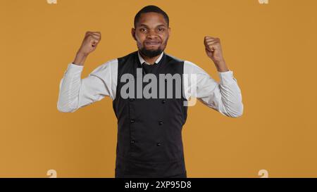 Waiter flexing his muscles and showing his strength in studio, acting ...