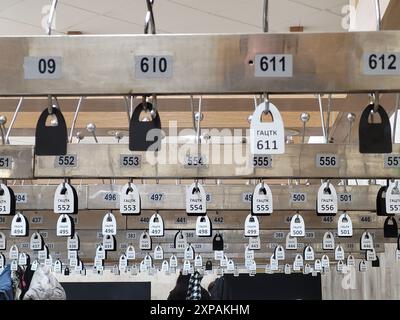 Coat check area with numbered tags hanging from metal racks. Person ...