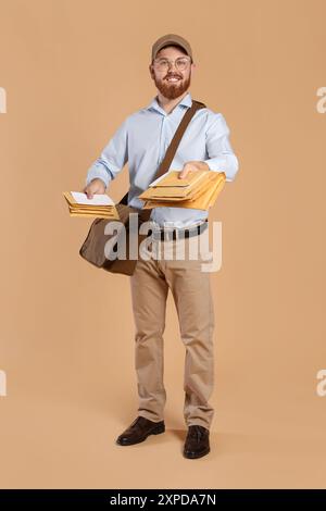 Happy young postman with leather bag delivering letters on brown ...