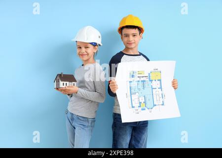 Little architects with house plan on blue background Stock Photo - Alamy