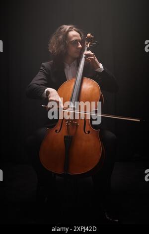 Vertical full shot of male classical music player holding cello while ...