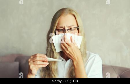 Sick exhausted woman sneezing blow nose using tissue and measuring ...