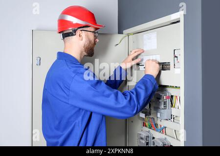 Electrician wearing uniform installing electricity meter indoors Stock ...