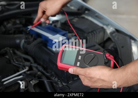 Auto mechanic with multimeter doing diagnostic at automobile repair ...