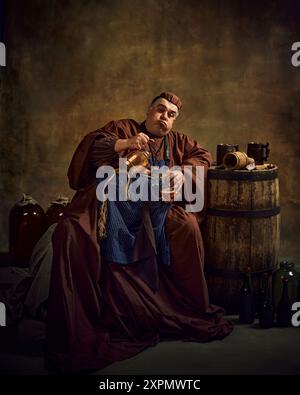 Medieval monk in period clothes pouring beer into mug from kettle ...