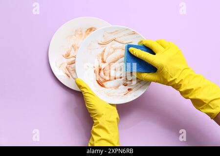 Hands washing dishes on lilac background Stock Photo - Alamy