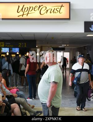 Man standing under "Upper Crust" logo at Lanzarote Airport Stock Photo ...