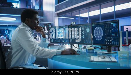 Black Male Neuroscientist Using Desktop Computer To Analyze MRI Scans Of Brain In Medical ...