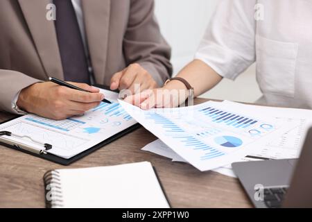 Consultant working with client at wooden table in office, closeup ...