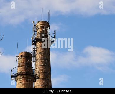 Two tall brick chimneys above abandoned boiler building for venting ...